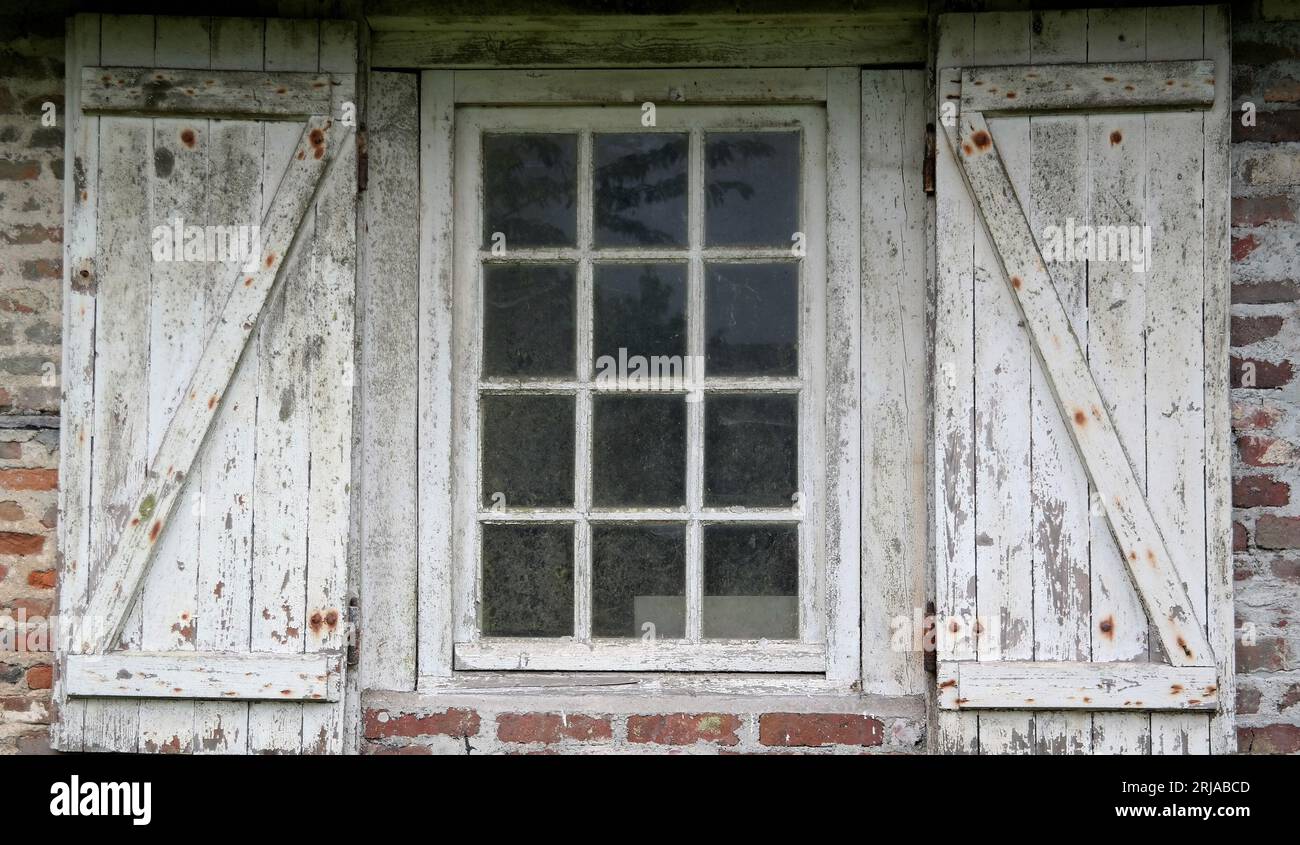 An old window with weathered wooden shutters. A front view of a paned ...