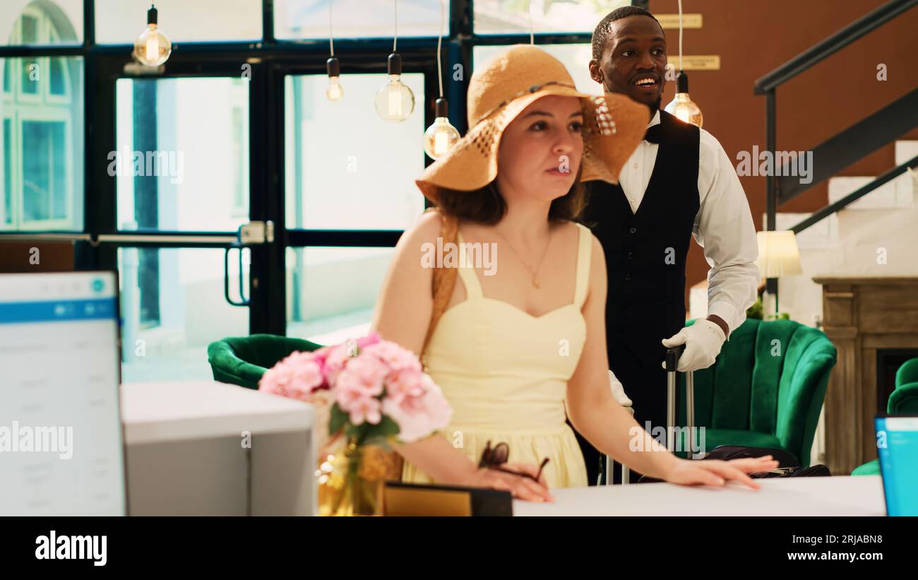 Female tourist entering tropical hotel lobby, approaching front desk to ...