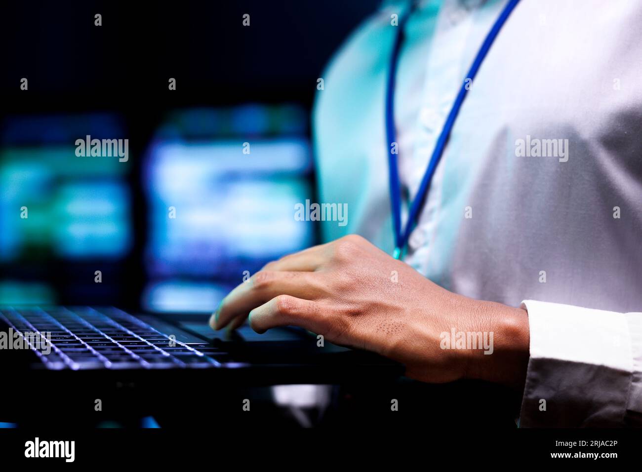 Computer scientist using laptop to analyze server cabinets providing ...