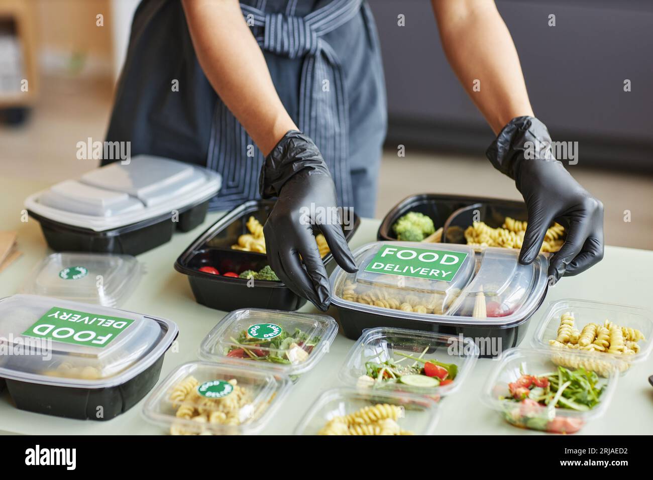 Closeup of unrecognizable woman carefully packing food delivery orders ...