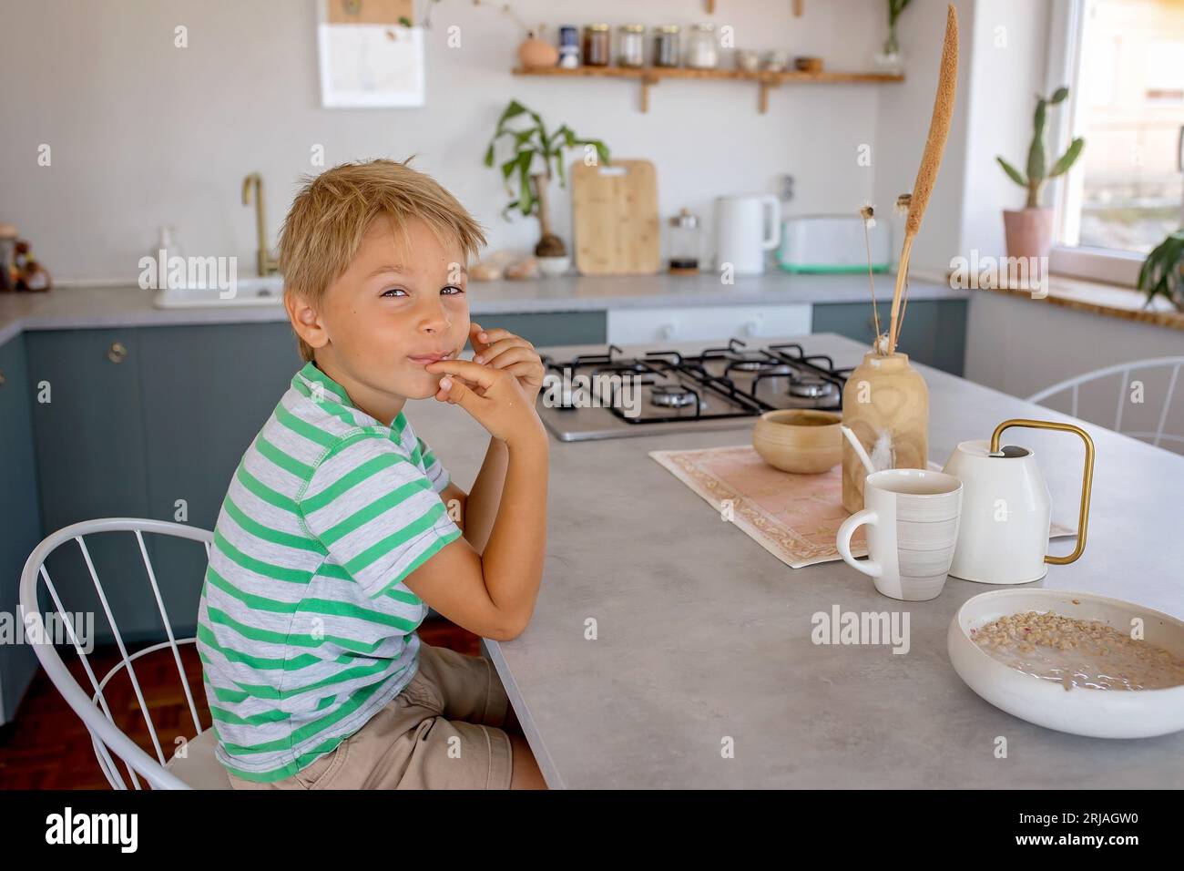 Beautiful blond child, boy, eating cereal for breakfast at home in the ...