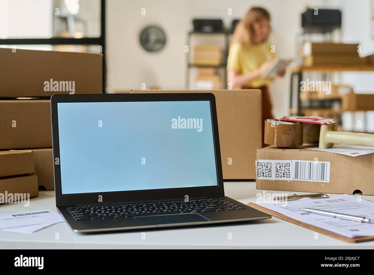 White screen of laptop standing on desk among packed cardboard boxes ...