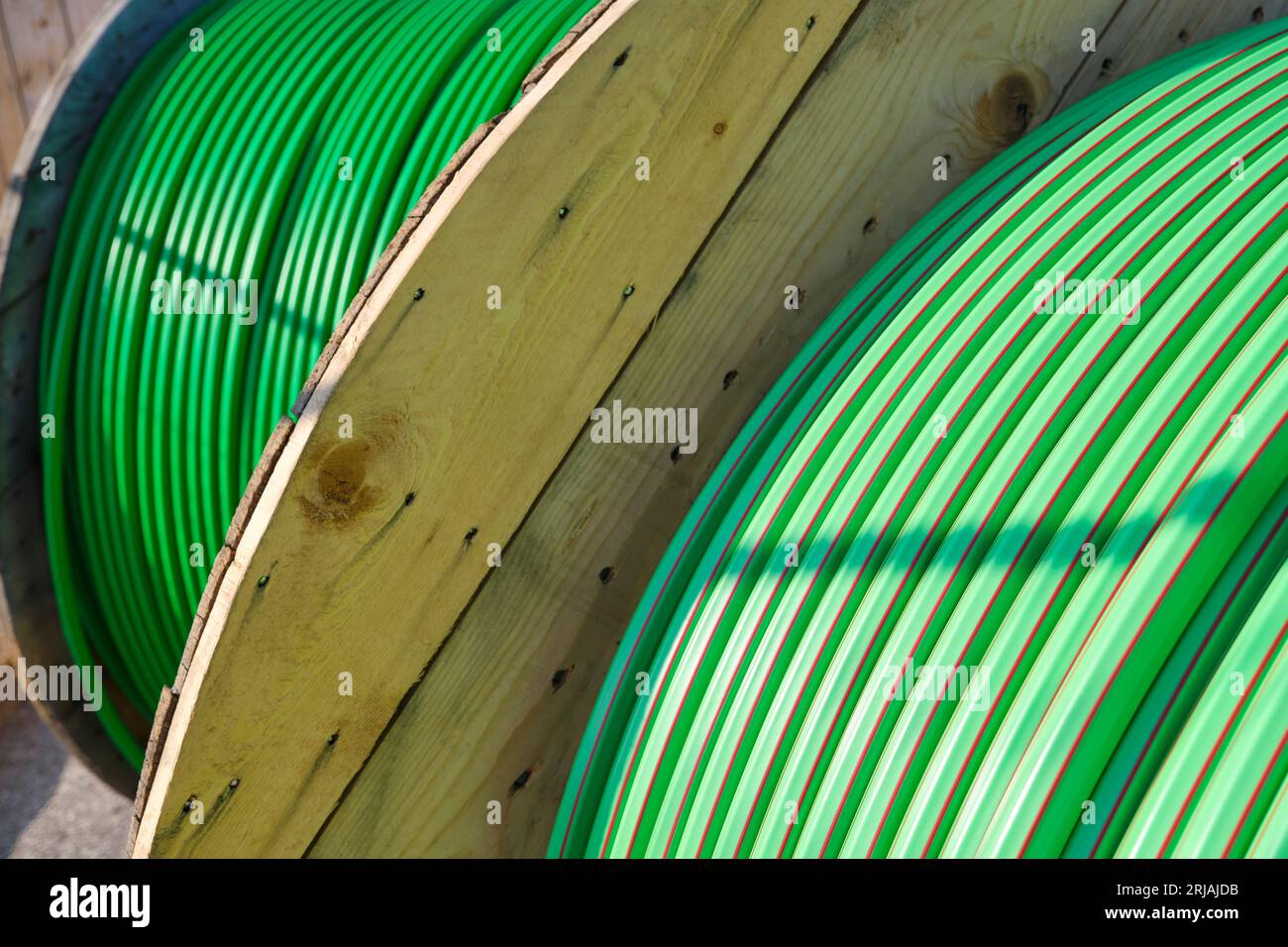 Wooden rolls of green colored industrial tube cable for underground ...