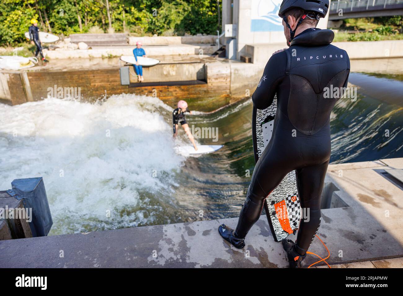 Nuremberg, Germany. 22nd Aug, 2023. A surfer stands with his surfboard next to the Nuremberg ...