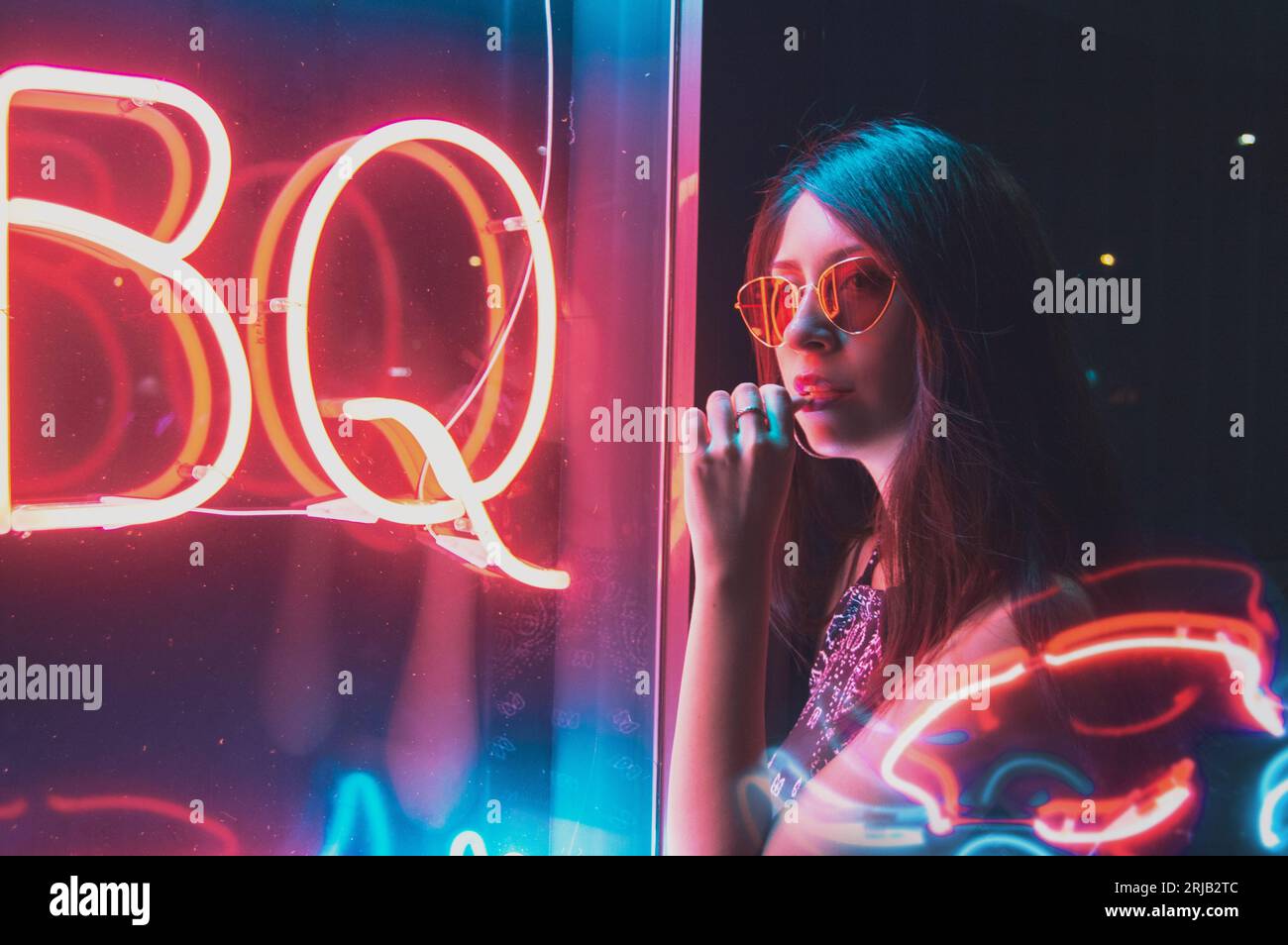 A teenage girl next to a window with colorful neon lights Stock Photo ...
