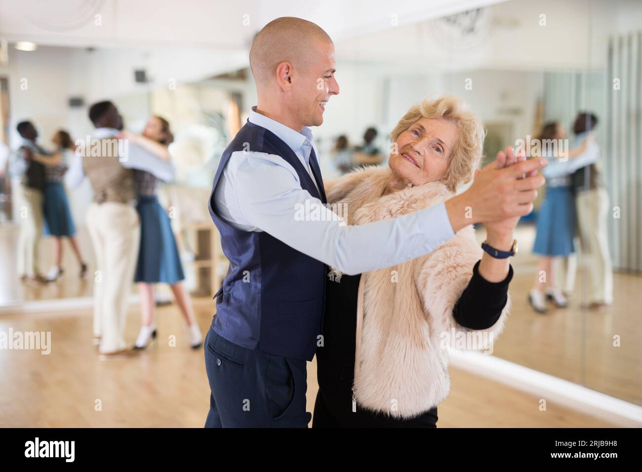 Elderly woman learning ballroom dancing movements in pair Stock Photo ...