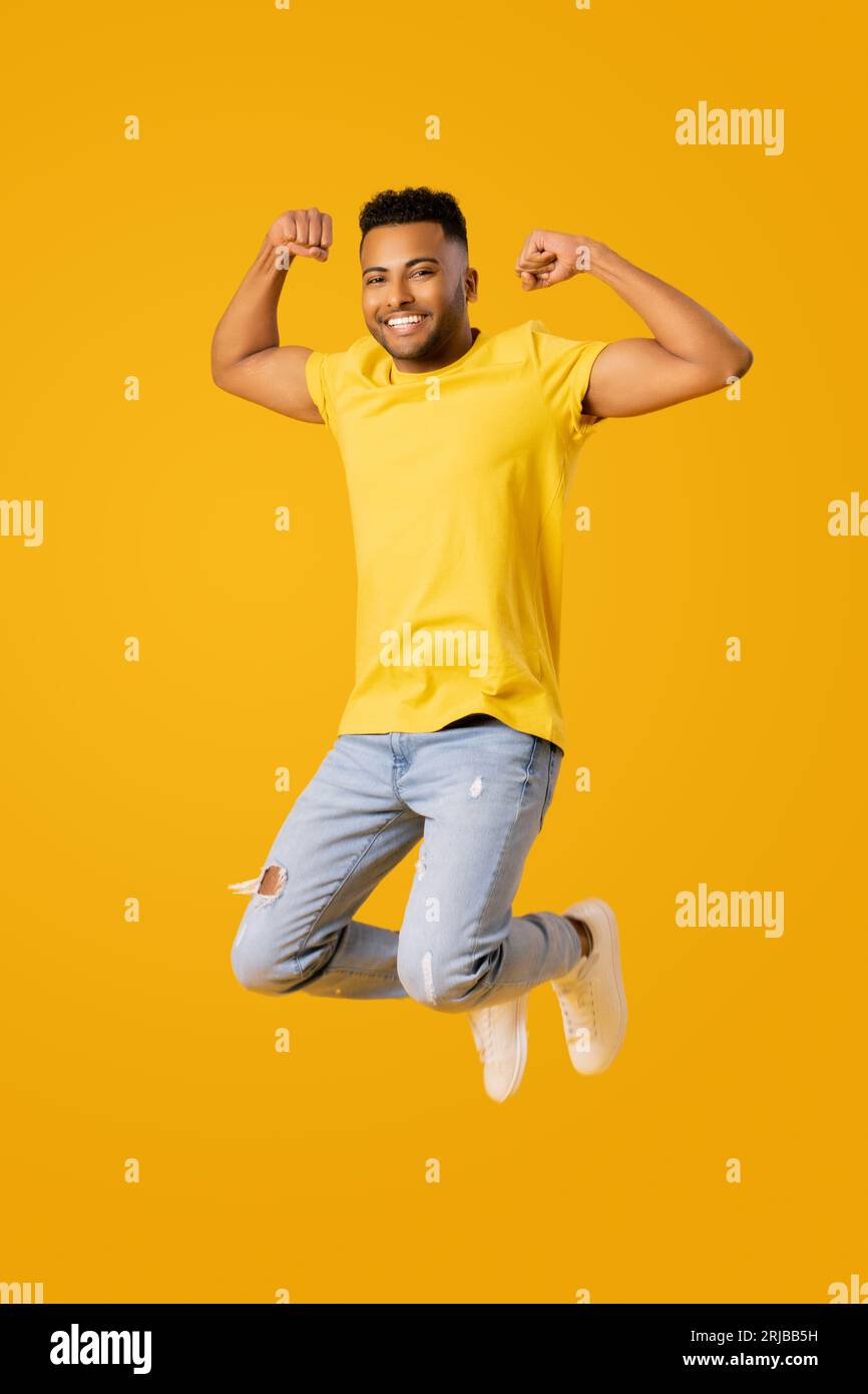 Full length portrait of overjoyed athletic indian guy jumping high and ...