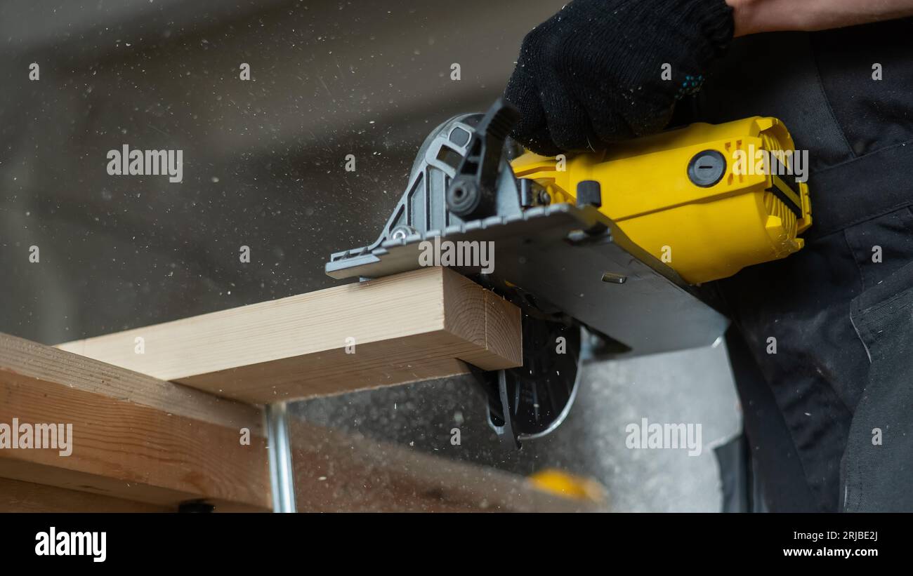 Master cuts the board with a circular saw in the workshop. Close-up of ...