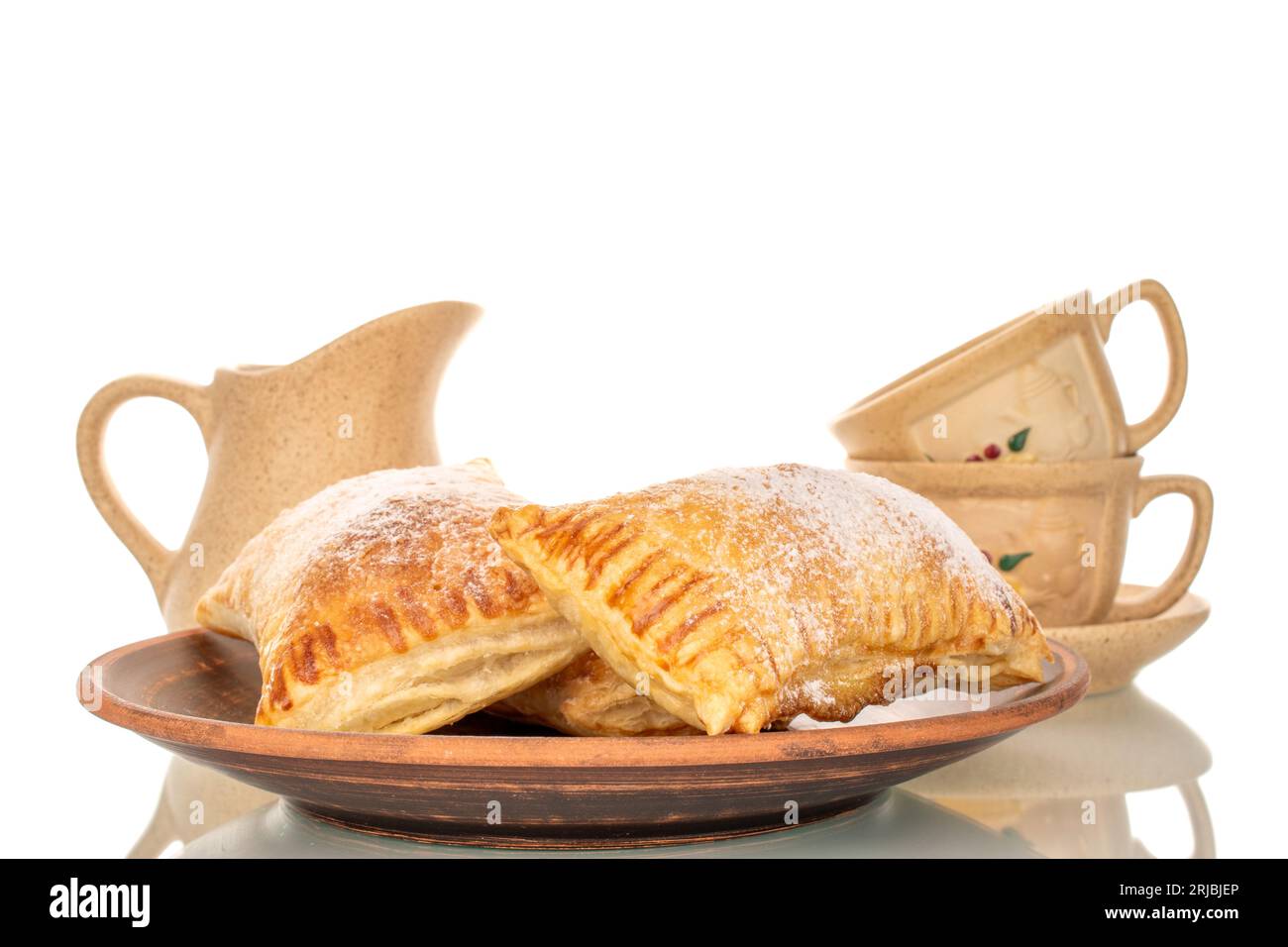 Three aromatic puff pastry buns with apples on a clay plate with two ...