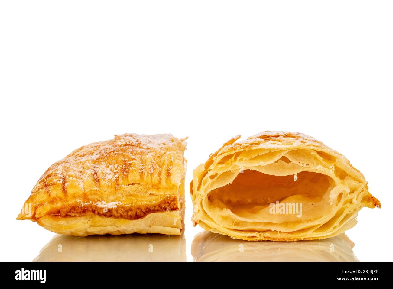 One aromatic puff pastry bun with apples cut in half, macro, isolated ...