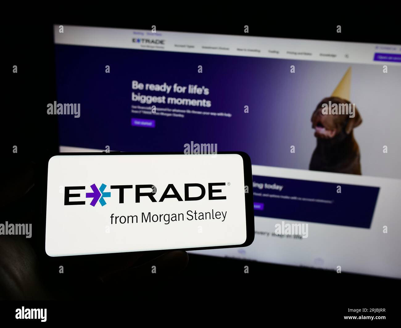 Person holding mobile phone with logo of American company E-Trade ...