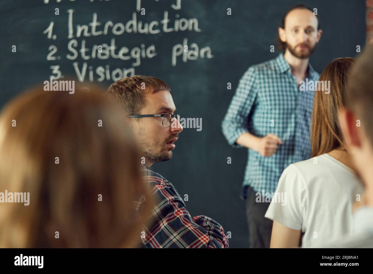 Business and leadership seminar. Speakers giving talk at business briefing. Rear view of team ...