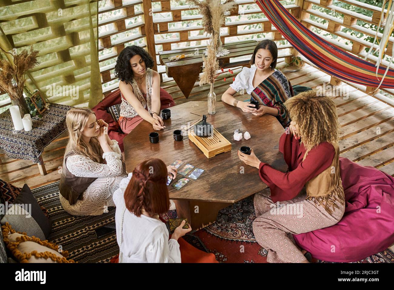multiethnic boho style girlfriends at wooden table with tarot cards and ...