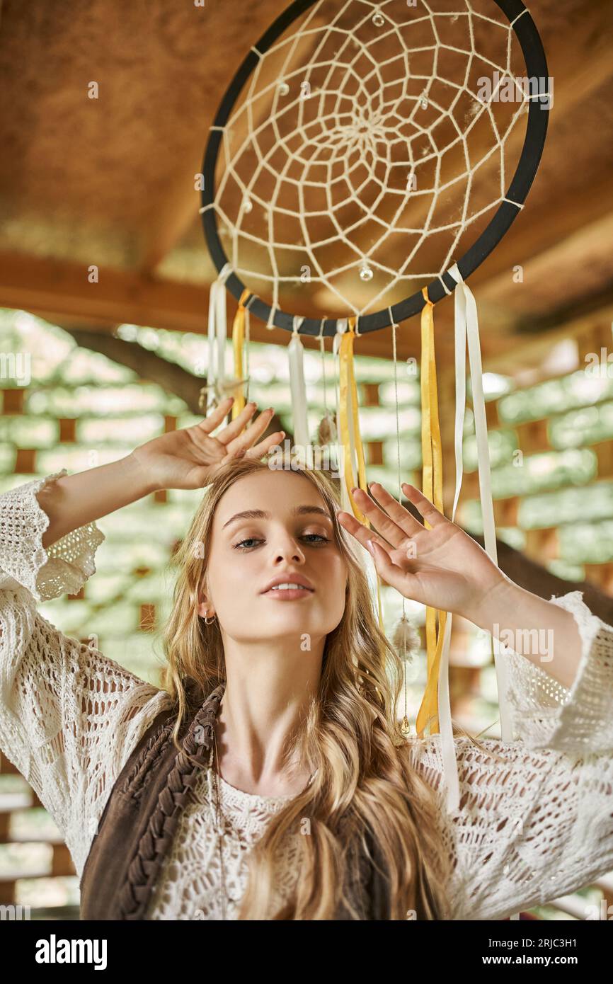 portrait of young boho style woman posing near dream catcher in cottage ...