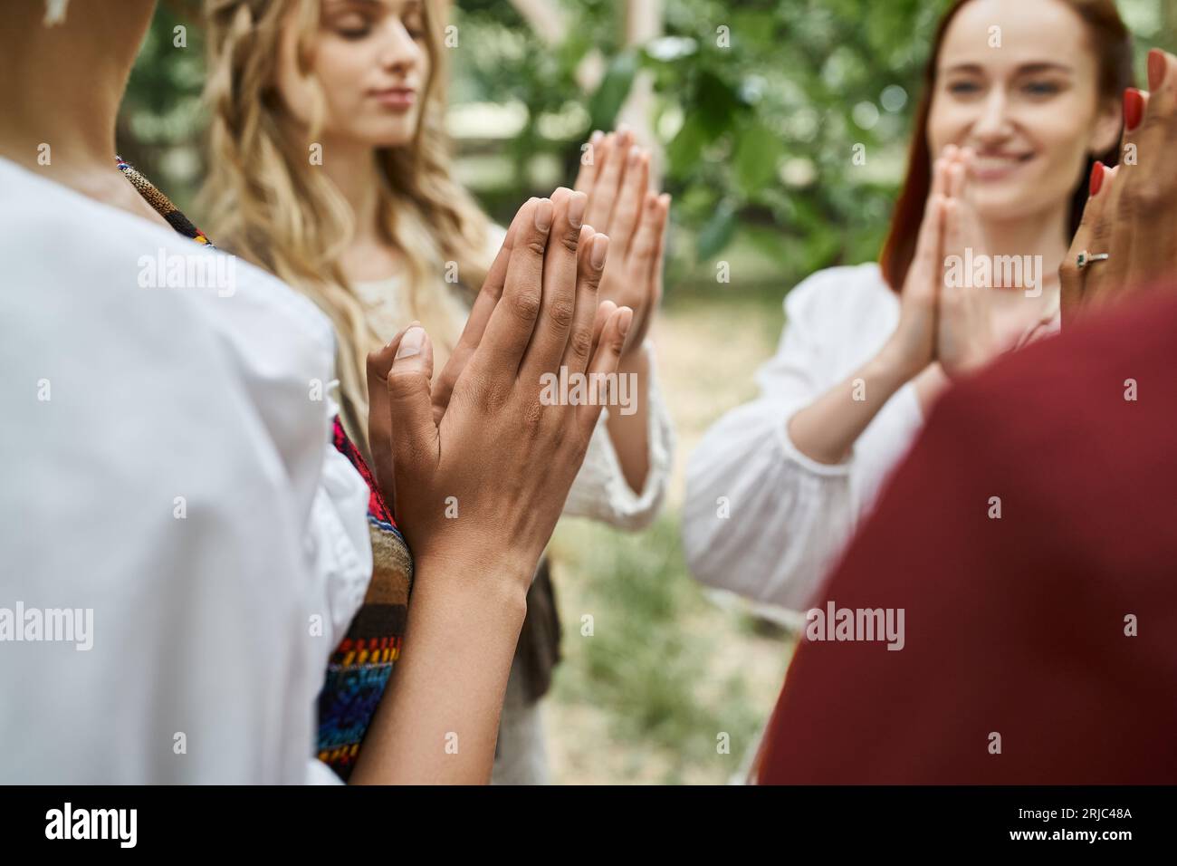 multiethnic women in boho clothes praying and meditating together in ...
