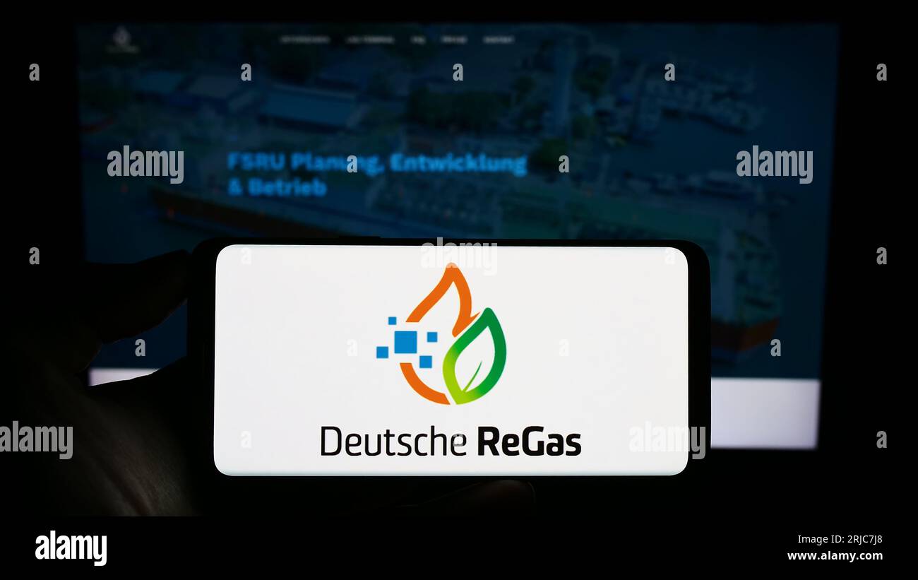 Person holding mobile phone with logo of German company Deutsche ReGas ...
