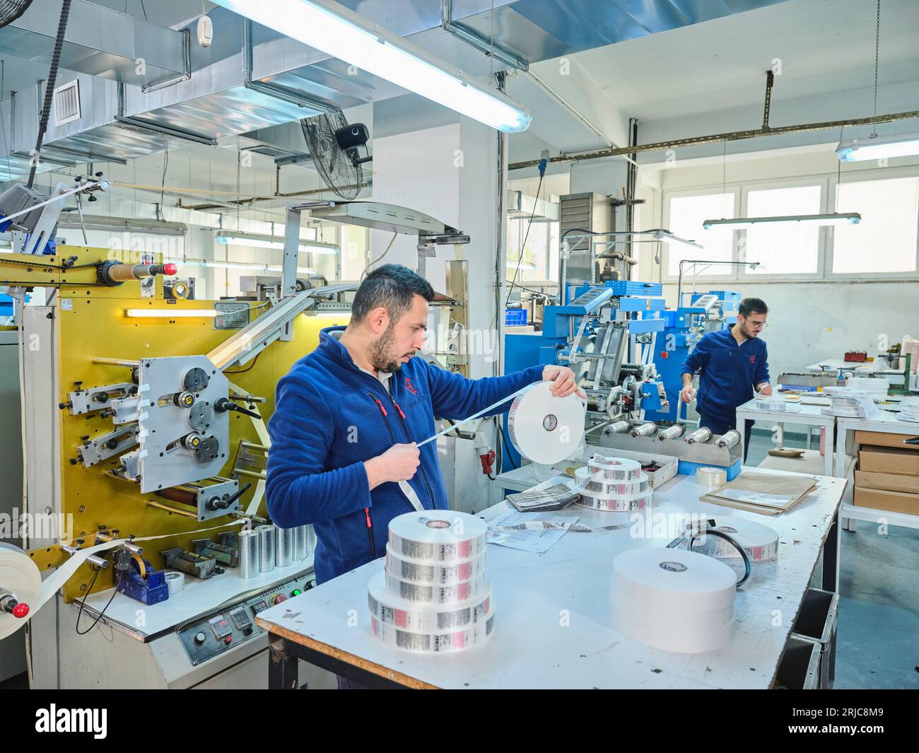 people working in a sticker printing factory. worker uses a stickier ...