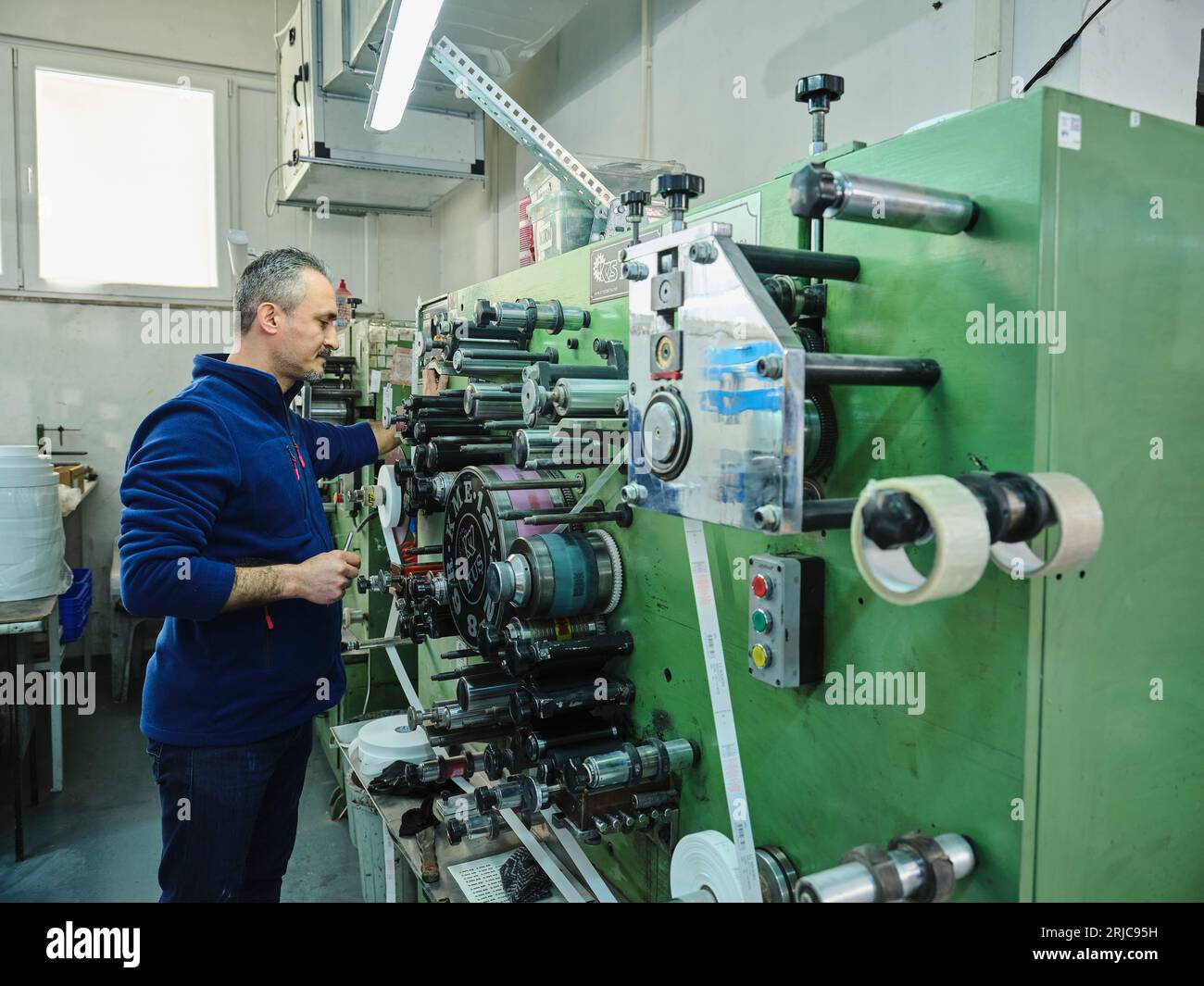 people working in a sticker printing factory. worker uses a stickier ...