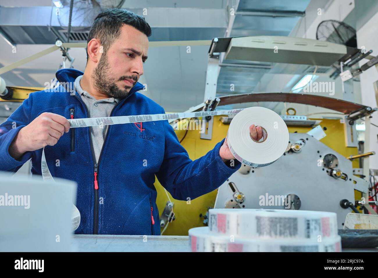people working in a sticker printing factory. worker uses a stickier ...