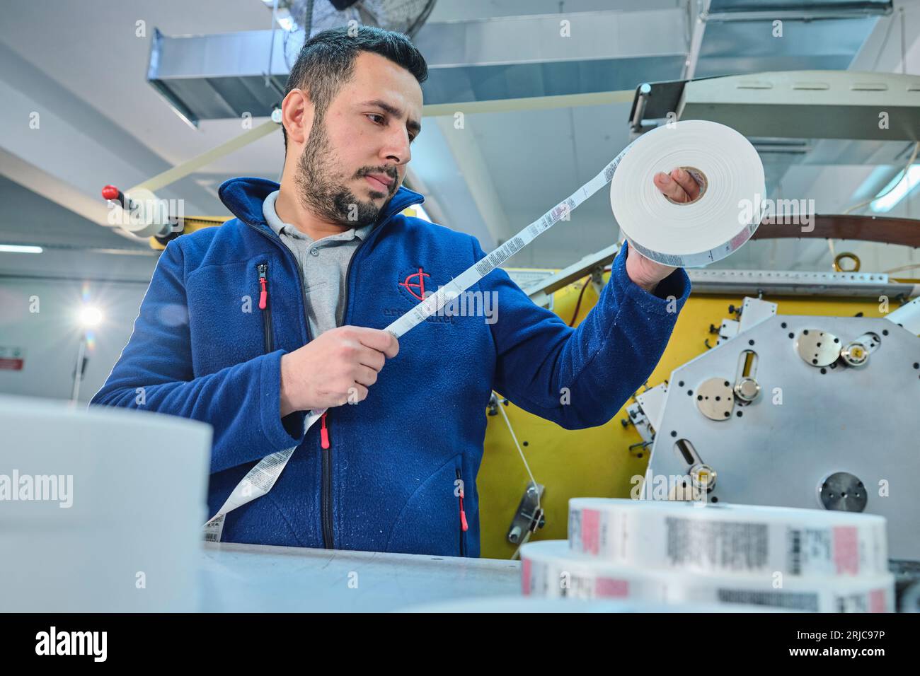 people working in a sticker printing factory. worker uses a stickier ...