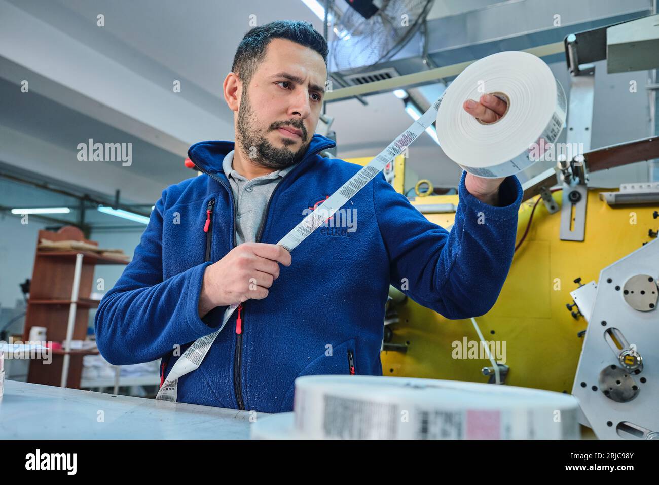 people working in a sticker printing factory. worker uses a stickier ...