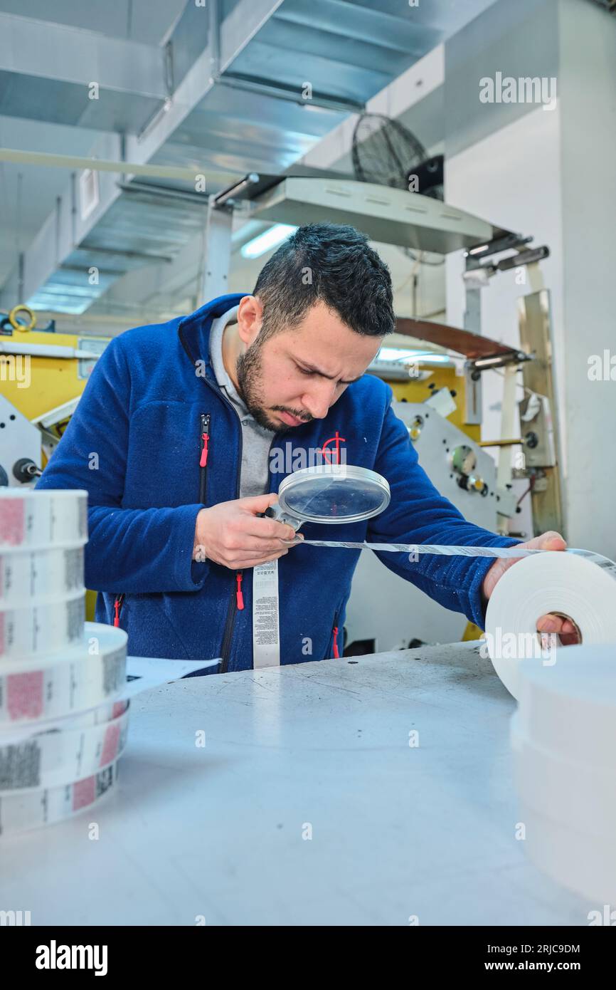 people working in a sticker printing factory. worker uses a stickier ...