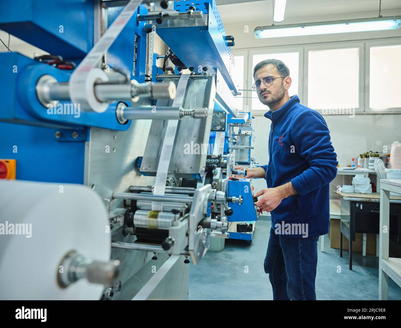 people working in a sticker printing factory. worker uses a stickier ...