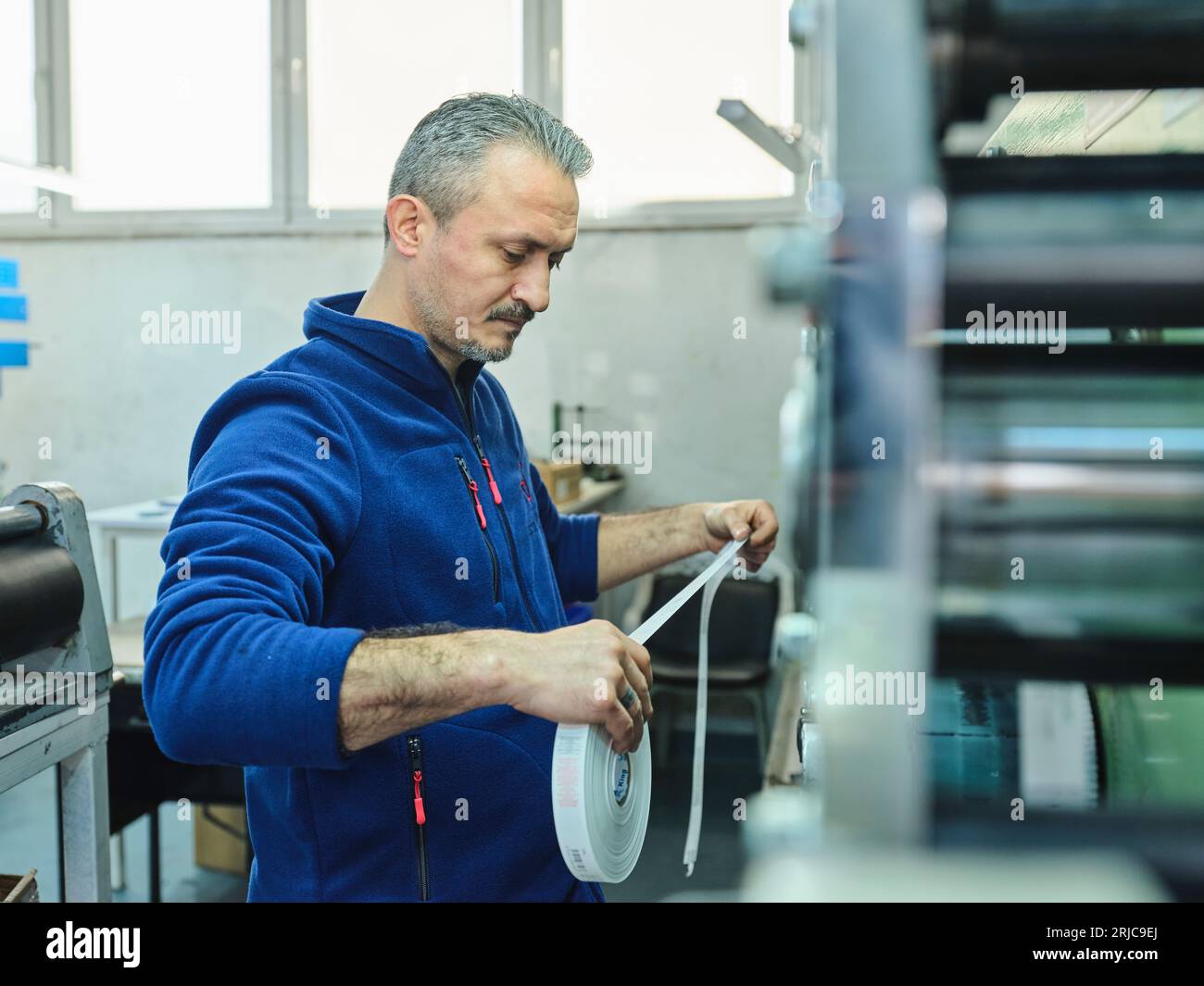 people working in a sticker printing factory. worker uses a stickier ...