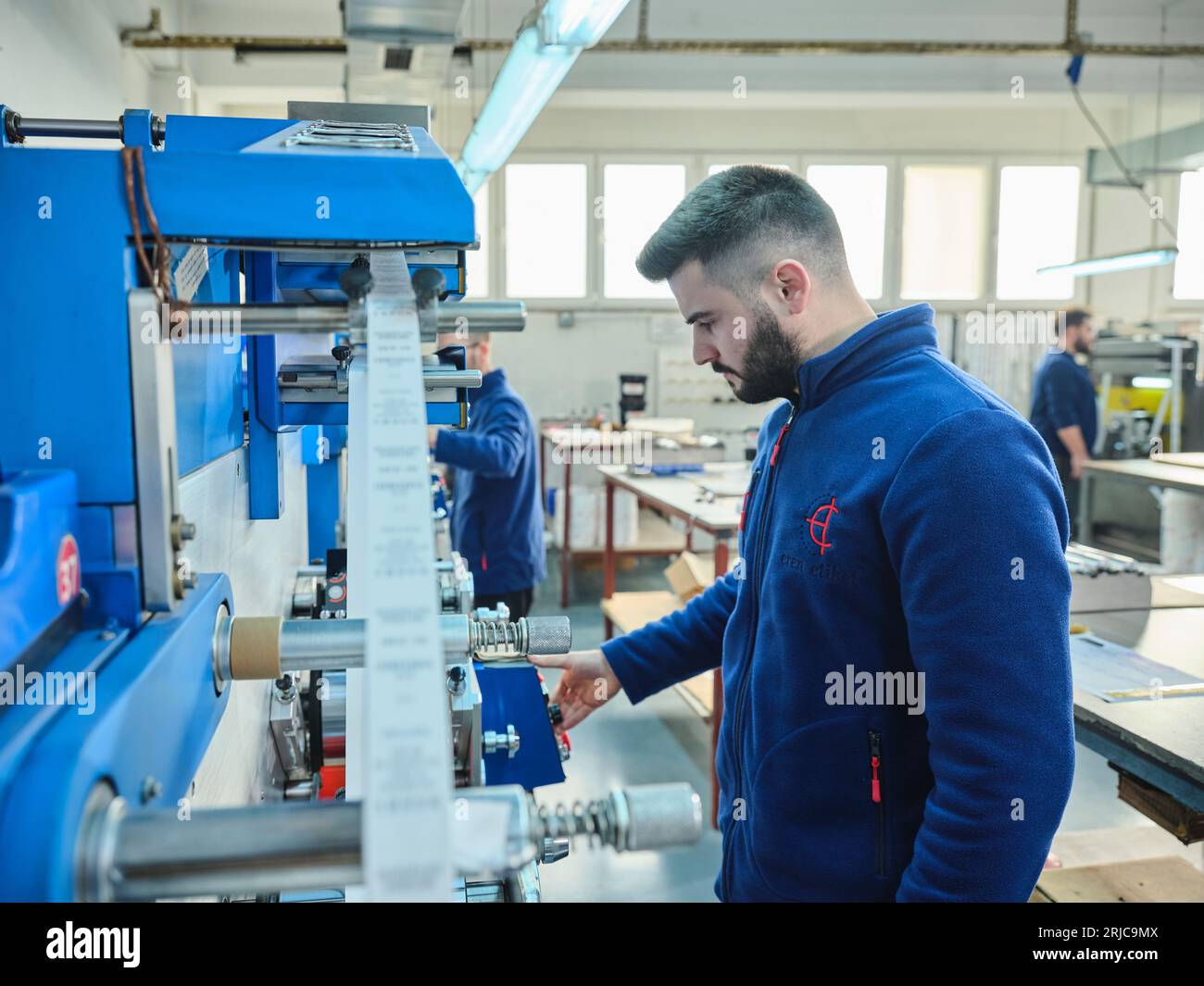 people working in a sticker printing factory. worker uses a stickier ...