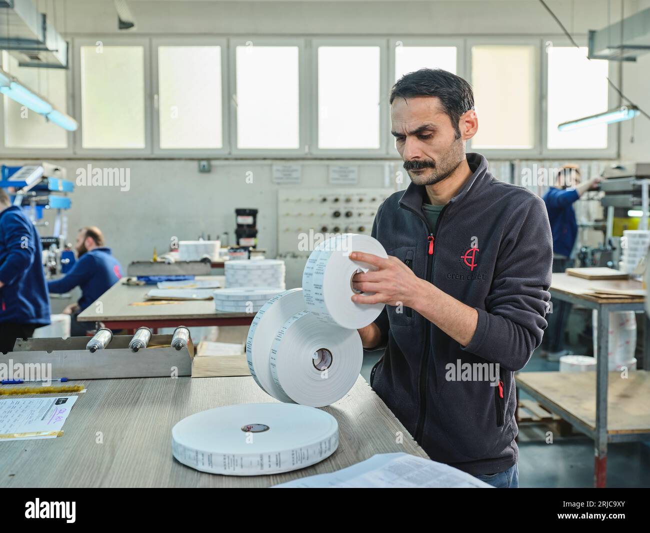 people working in a sticker printing factory. worker uses a stickier ...