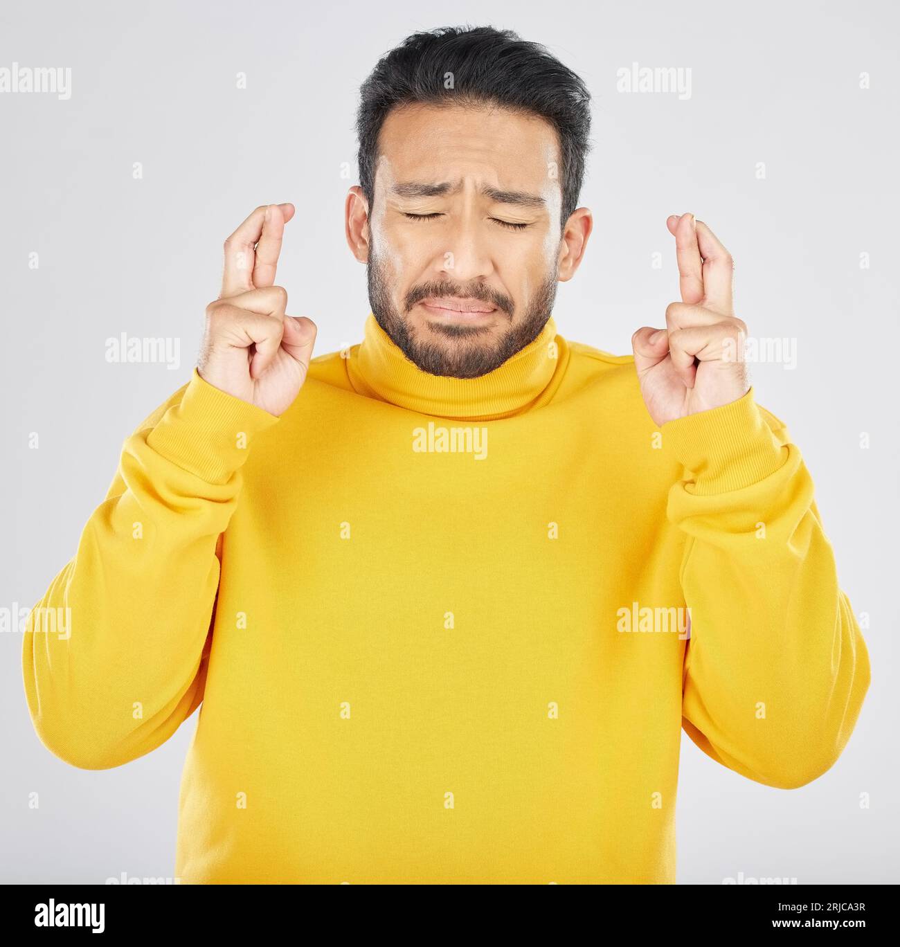 Nervous, face and fingers crossed by asian man in studio with anxiety ...