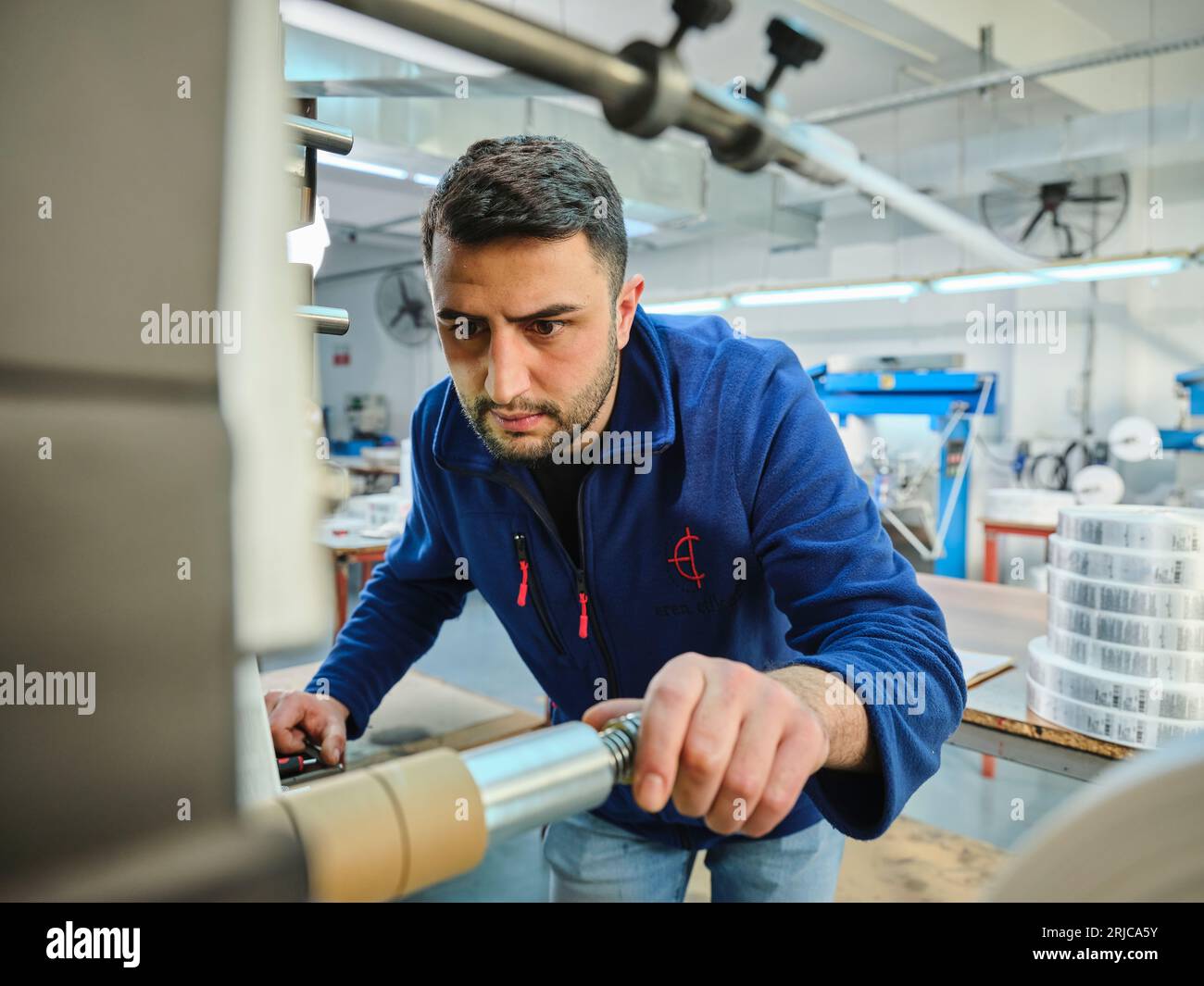 people working in a sticker printing factory. worker uses a stickier ...