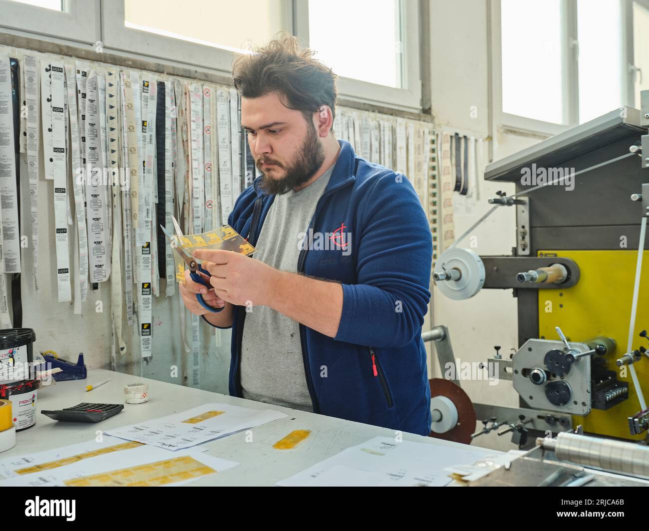 people working in a sticker printing factory. worker uses a stickier ...