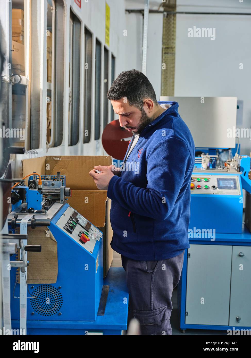 people working in a sticker printing factory. worker uses a stickier ...