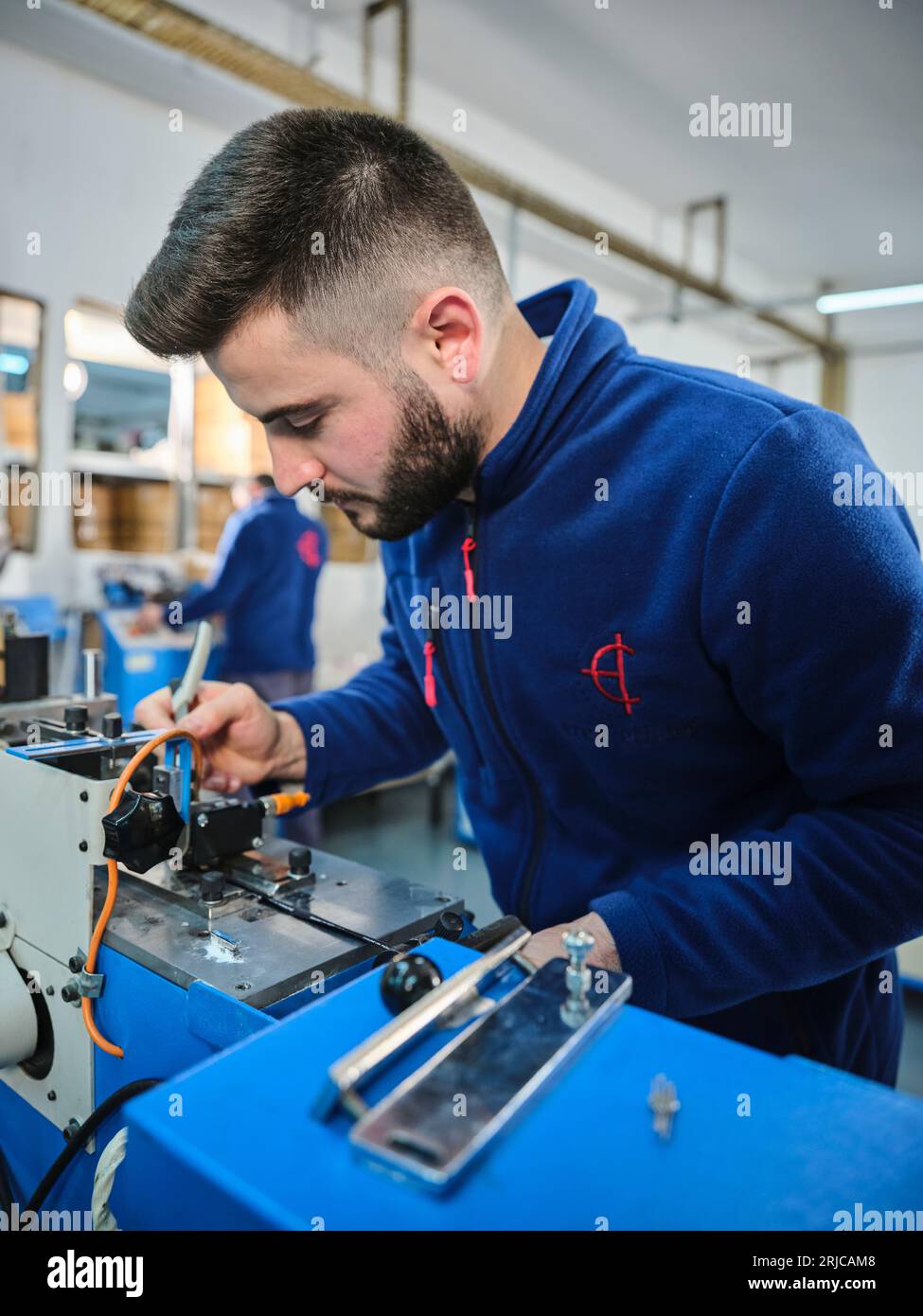 people working in a sticker printing factory. worker uses a stickier ...