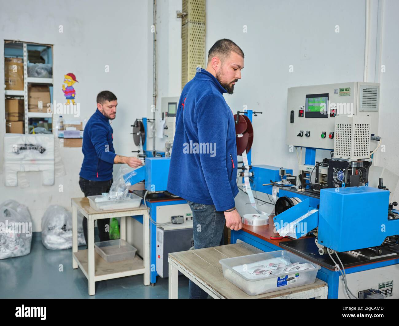 people working in a sticker printing factory. worker uses a stickier ...