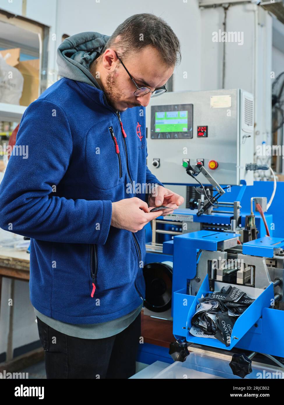 people working in a sticker printing factory. worker uses a stickier ...