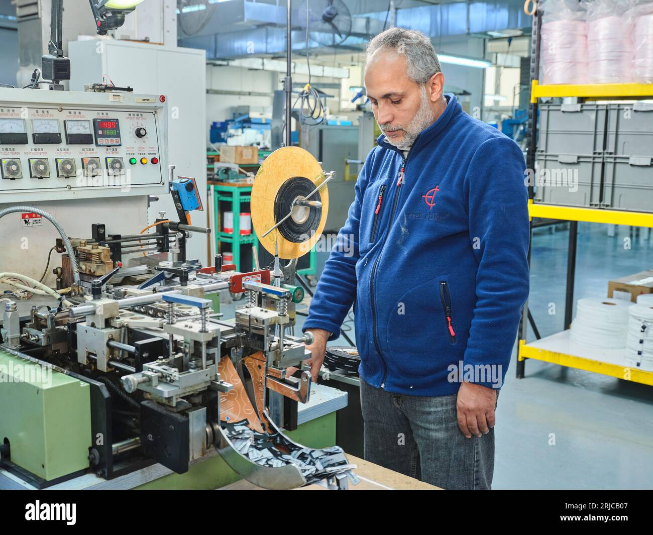 people working in a sticker printing factory. worker uses a stickier ...