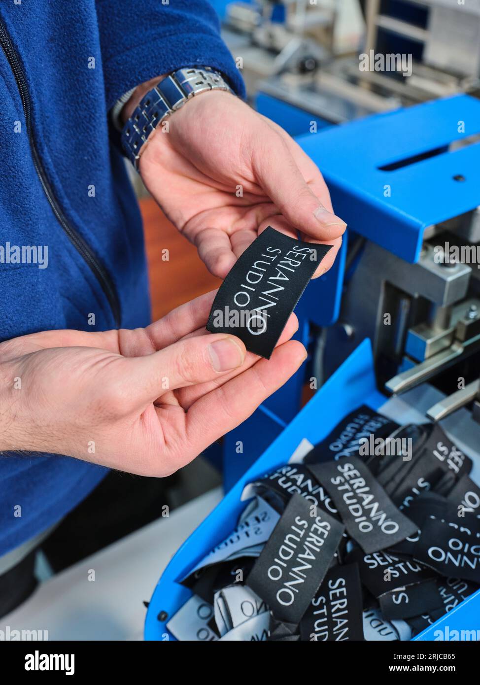 people working in a sticker printing factory. worker uses a stickier ...