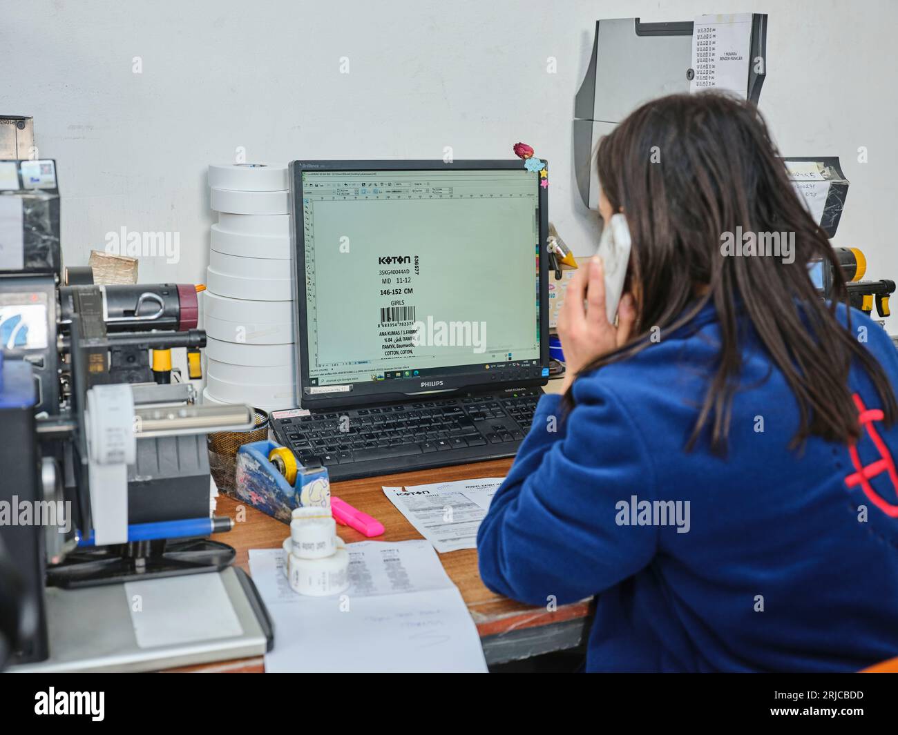 people working in a sticker printing factory. worker uses a stickier ...