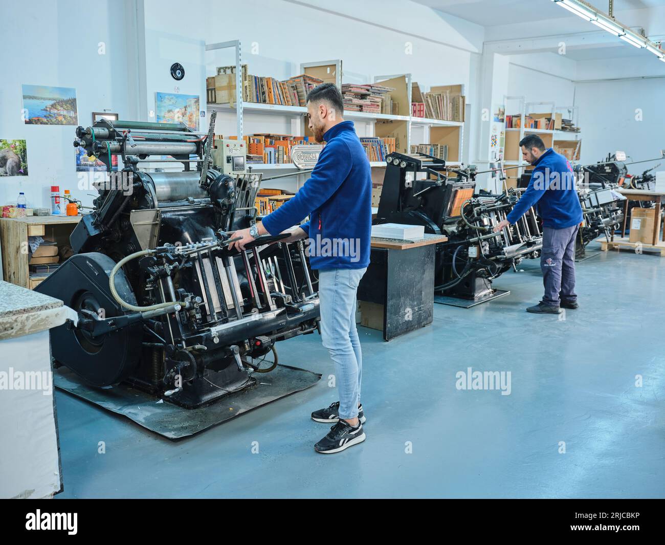 people working in a sticker printing factory. worker uses a stickier ...