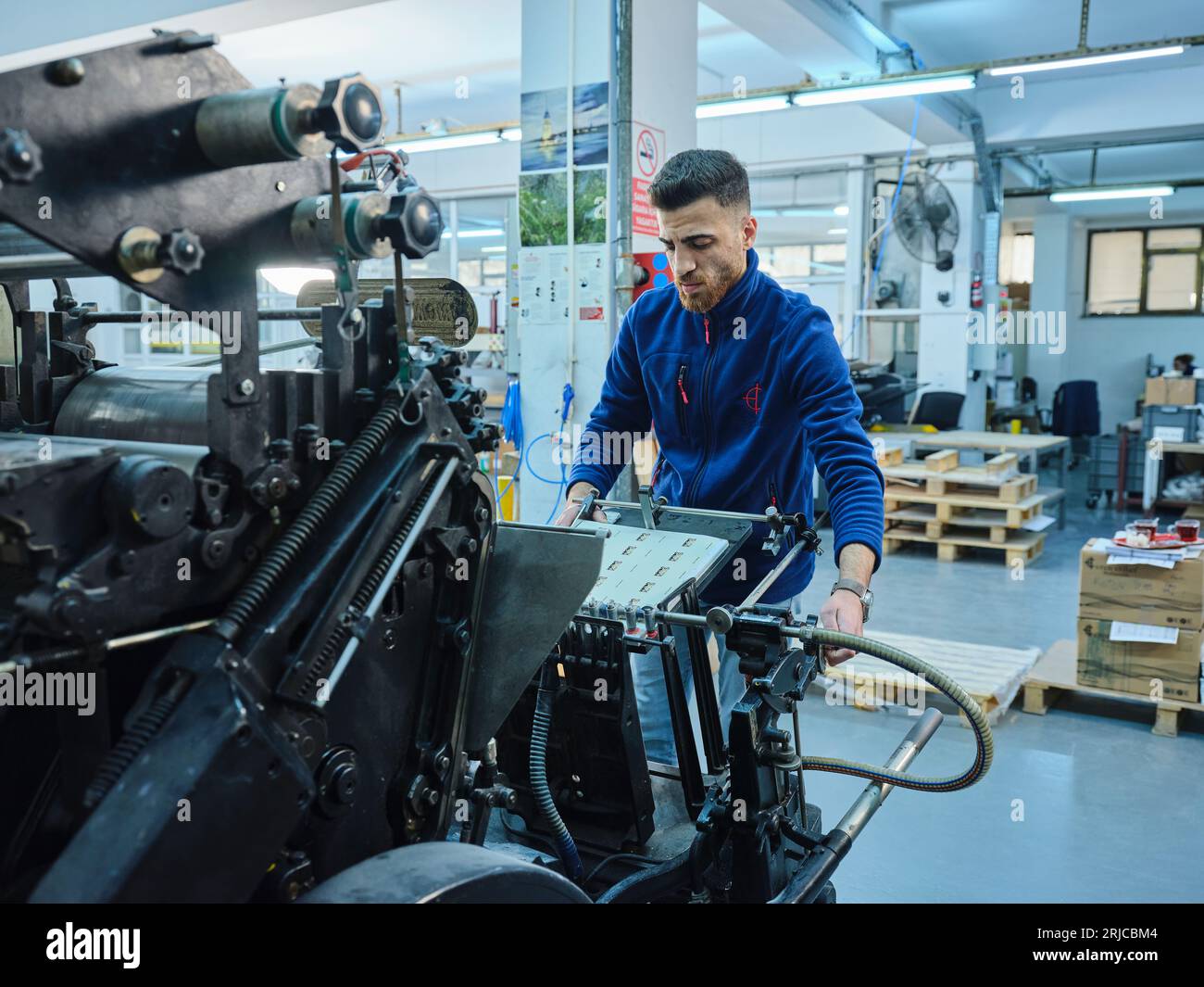 people working in a sticker printing factory. worker uses a stickier ...