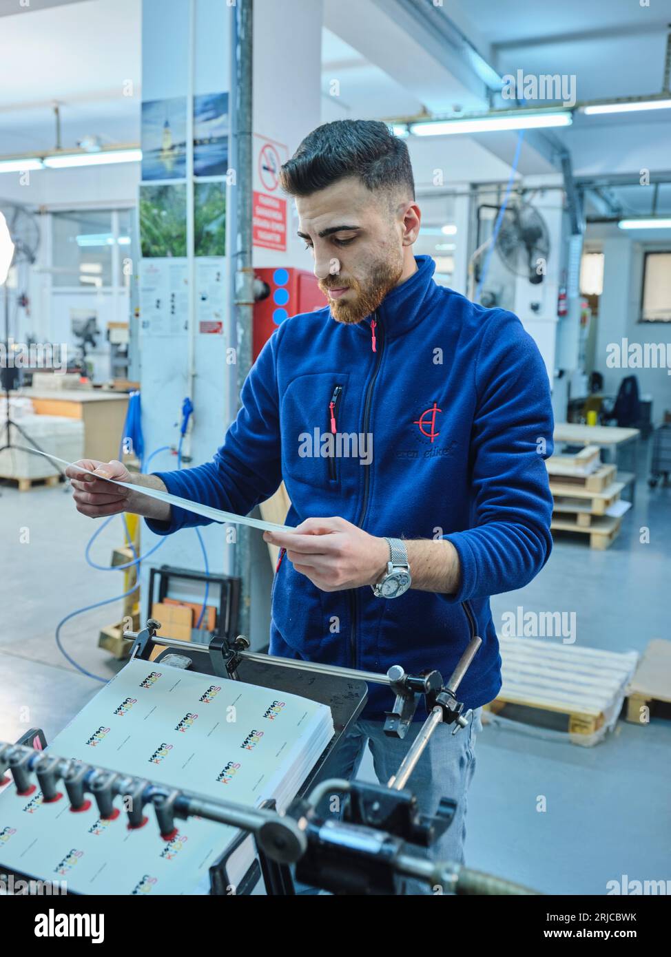 people working in a sticker printing factory. worker uses a stickier ...