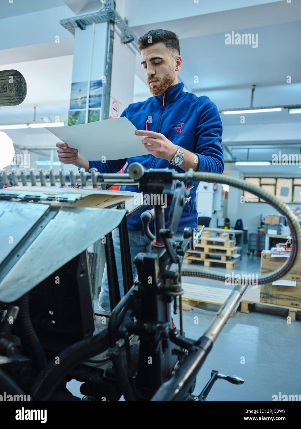 people working in a sticker printing factory. worker uses a stickier ...