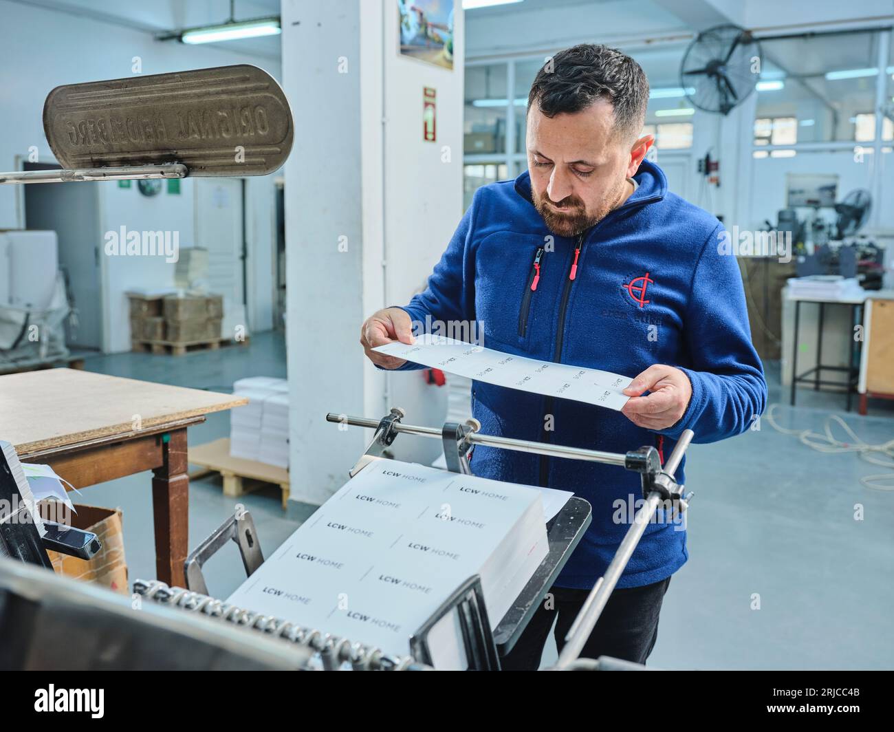 people working in a sticker printing factory. worker uses a stickier ...