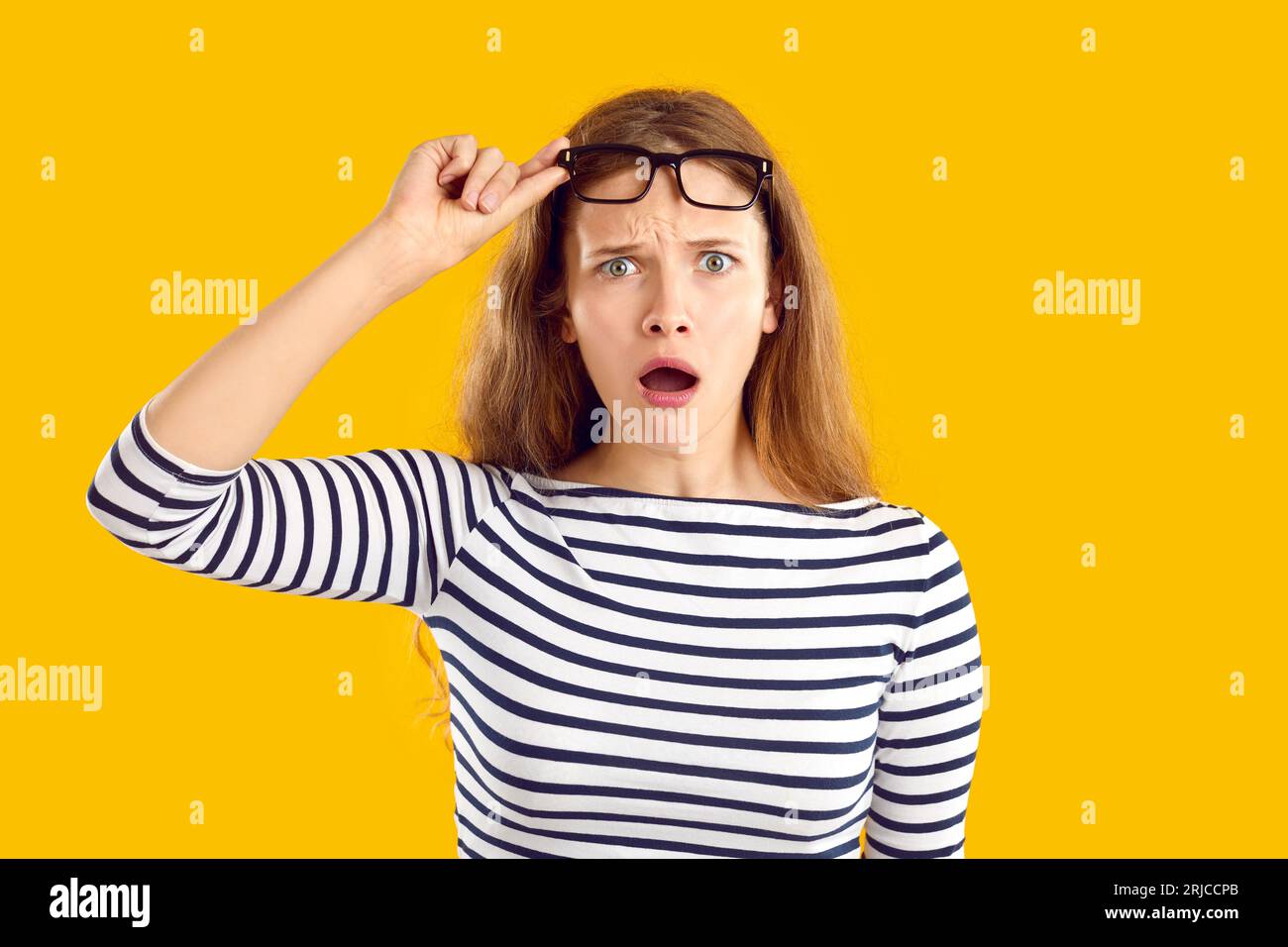 Young woman looking at something with a funny, confused, shocked face ...