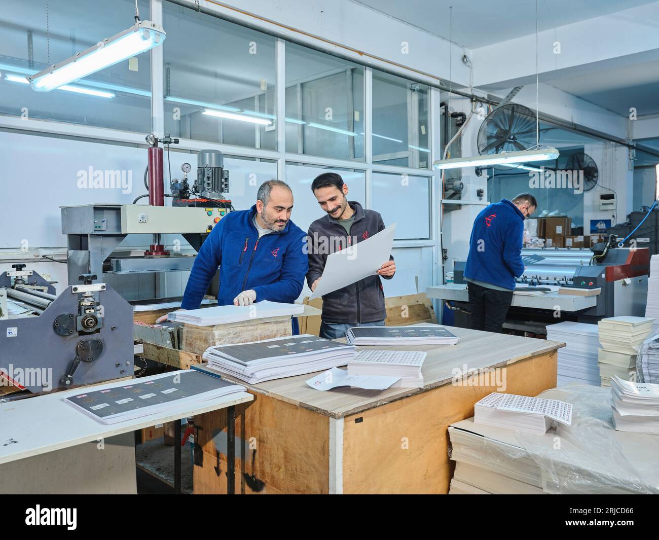 people working in a sticker printing factory. worker uses a stickier ...
