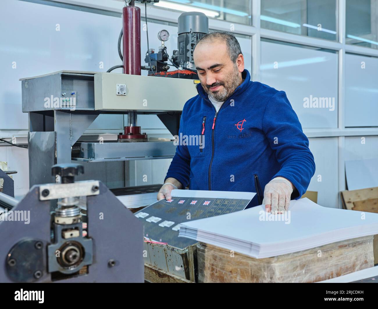 people working in a sticker printing factory. worker uses a stickier ...