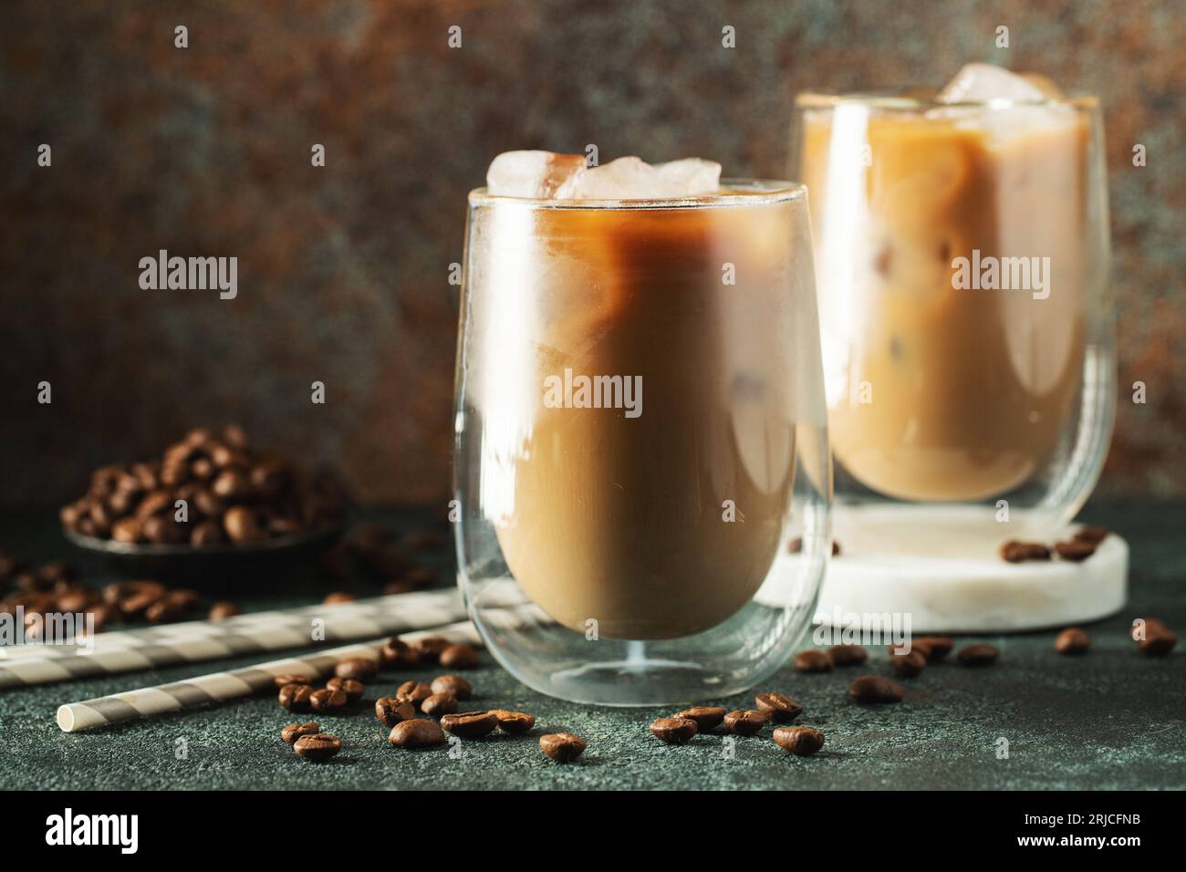 Ice coffee in a tall glass with cream poured over, ice cubes and beans ...