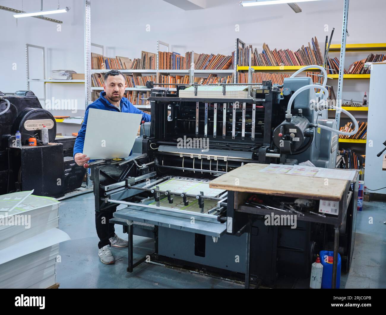 people working in a sticker printing factory. worker uses a stickier ...